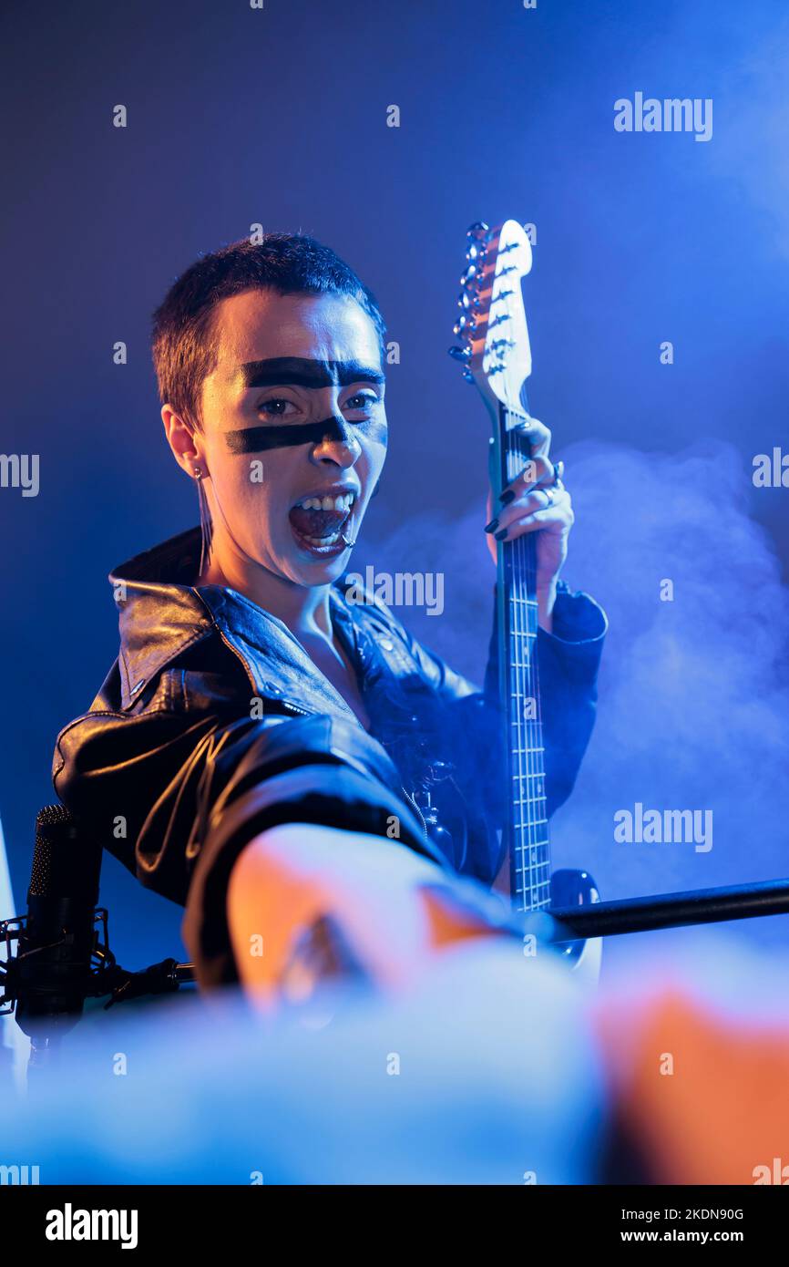 Crazy performer playing guitar singing loud, screaming and producing ...