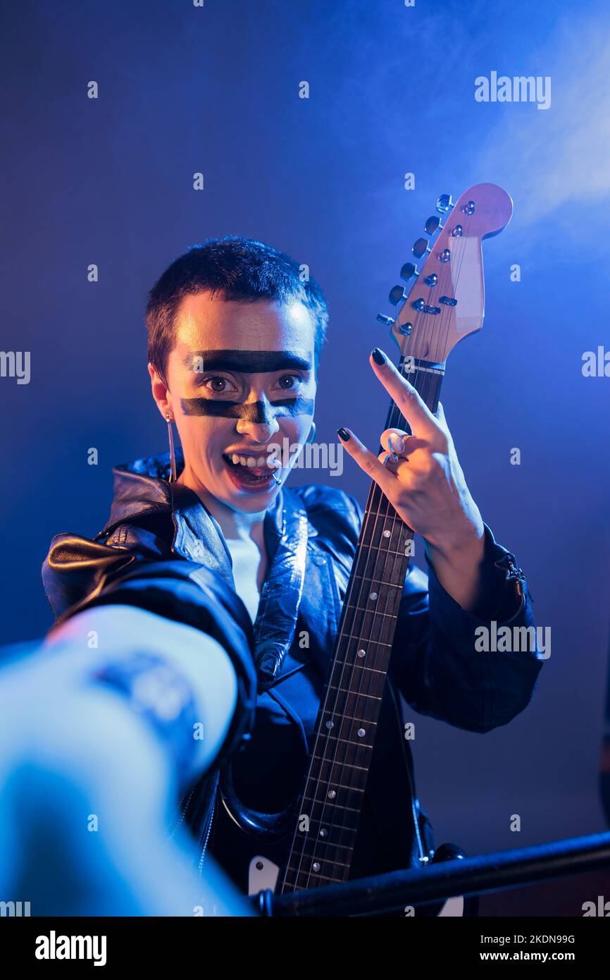 Punk rocker sticking tongue out doing rock sign, preparing to play ...