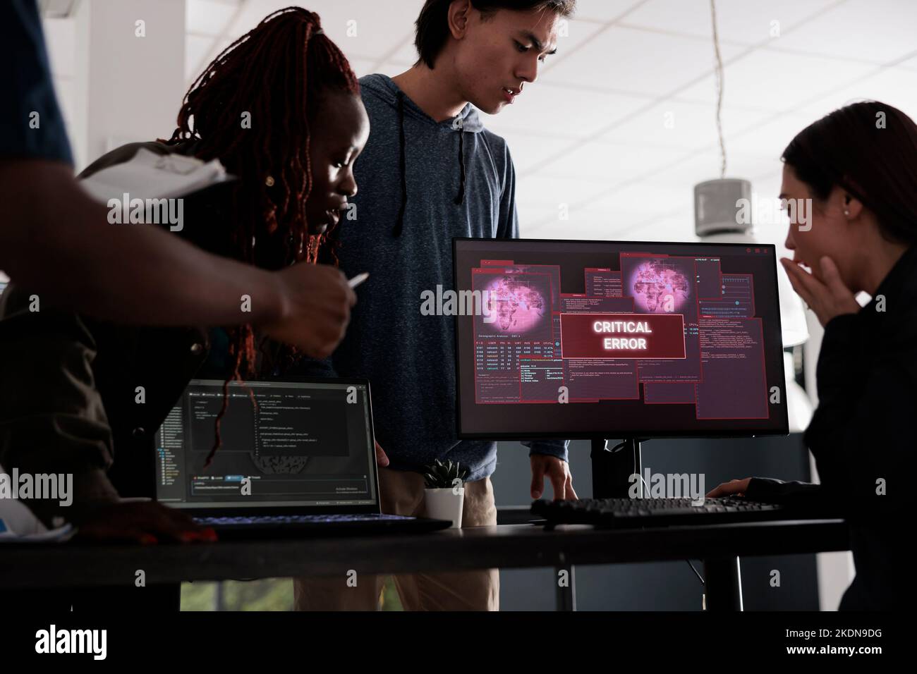 Team of software developers looking at monitor dealing with security breach alert on pc, trying ...