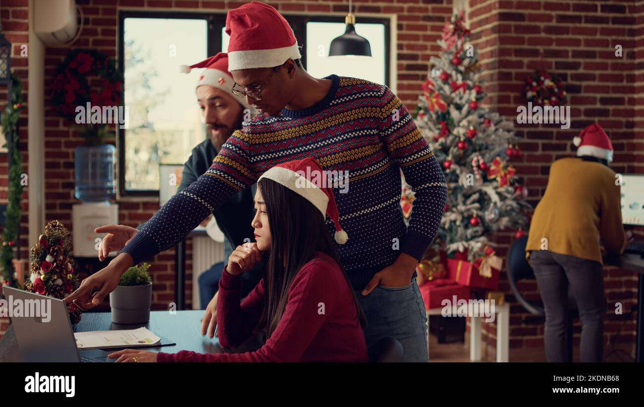 Diverse coworkers working on startup report in festive office, doing ...