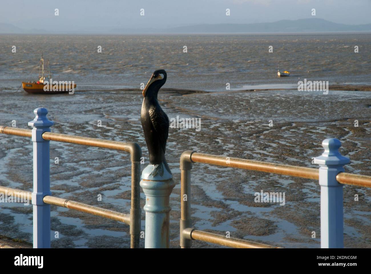 Sculpture of Cormorant on rail, Morecambe bay and the promenade ...