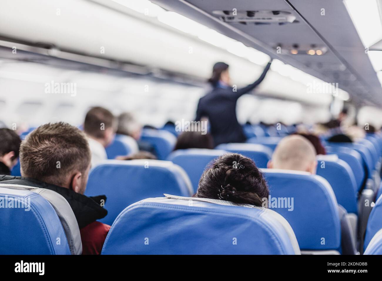 Interior of airplane with passengers on seats and stewardess walking ...