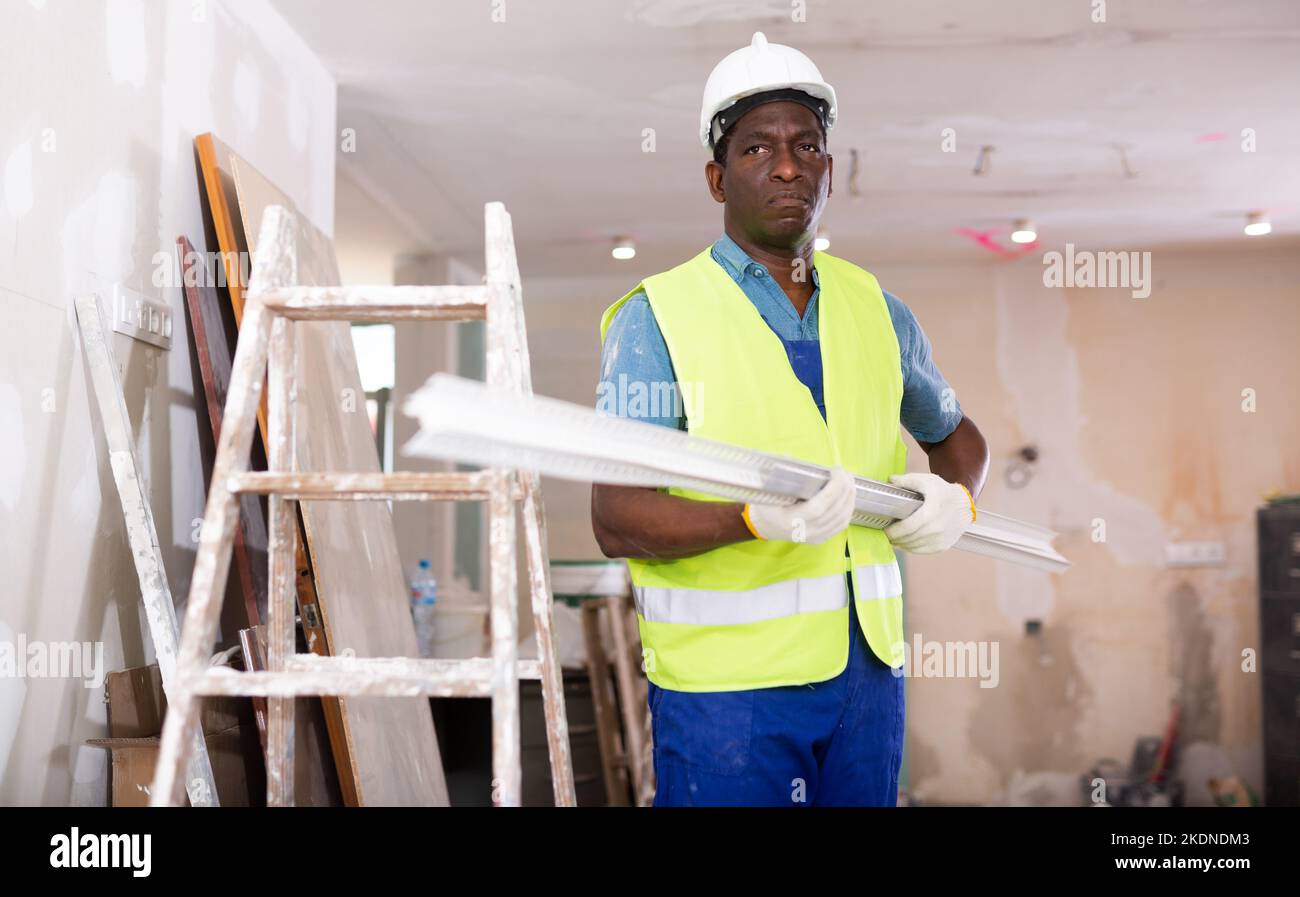 African-american man builder carrying metallic profile while working in ...