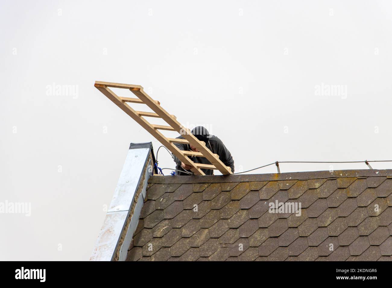 A repairman manipulates a ladder while repairing a roof Stock Photo - Alamy