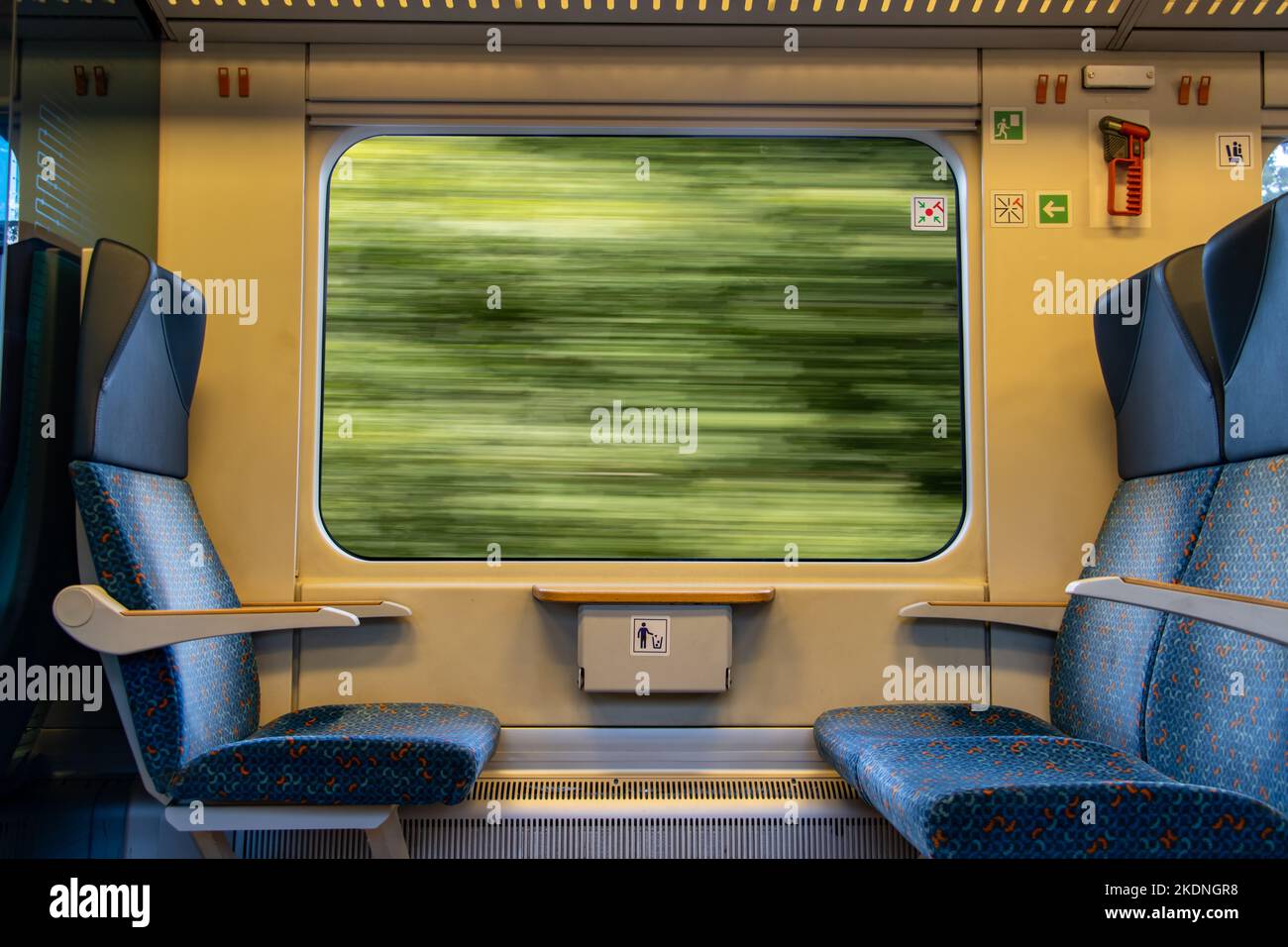 The interior of a passenger train with a view of passing trees outside ...