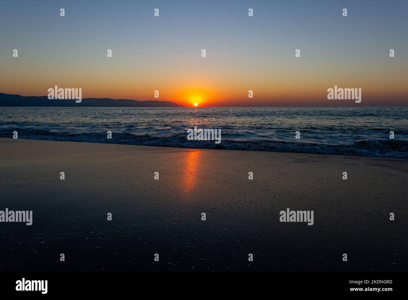 An Ocean Wave Is Breaking Against A Colorful Sunset Sky Stock Photo - Alamy