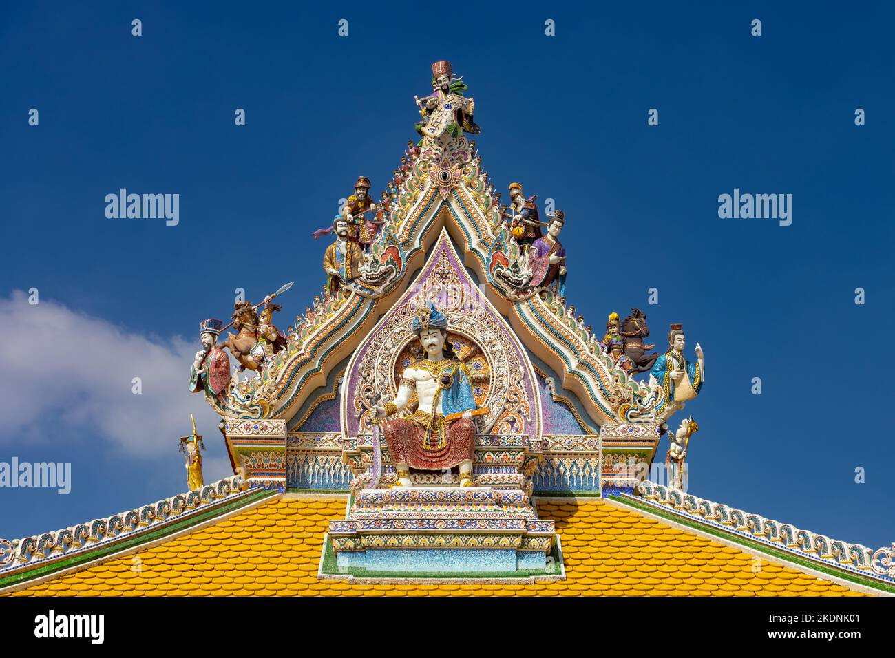 Ornate shield with figures on the roof of Buddhist temple with blue sky ...