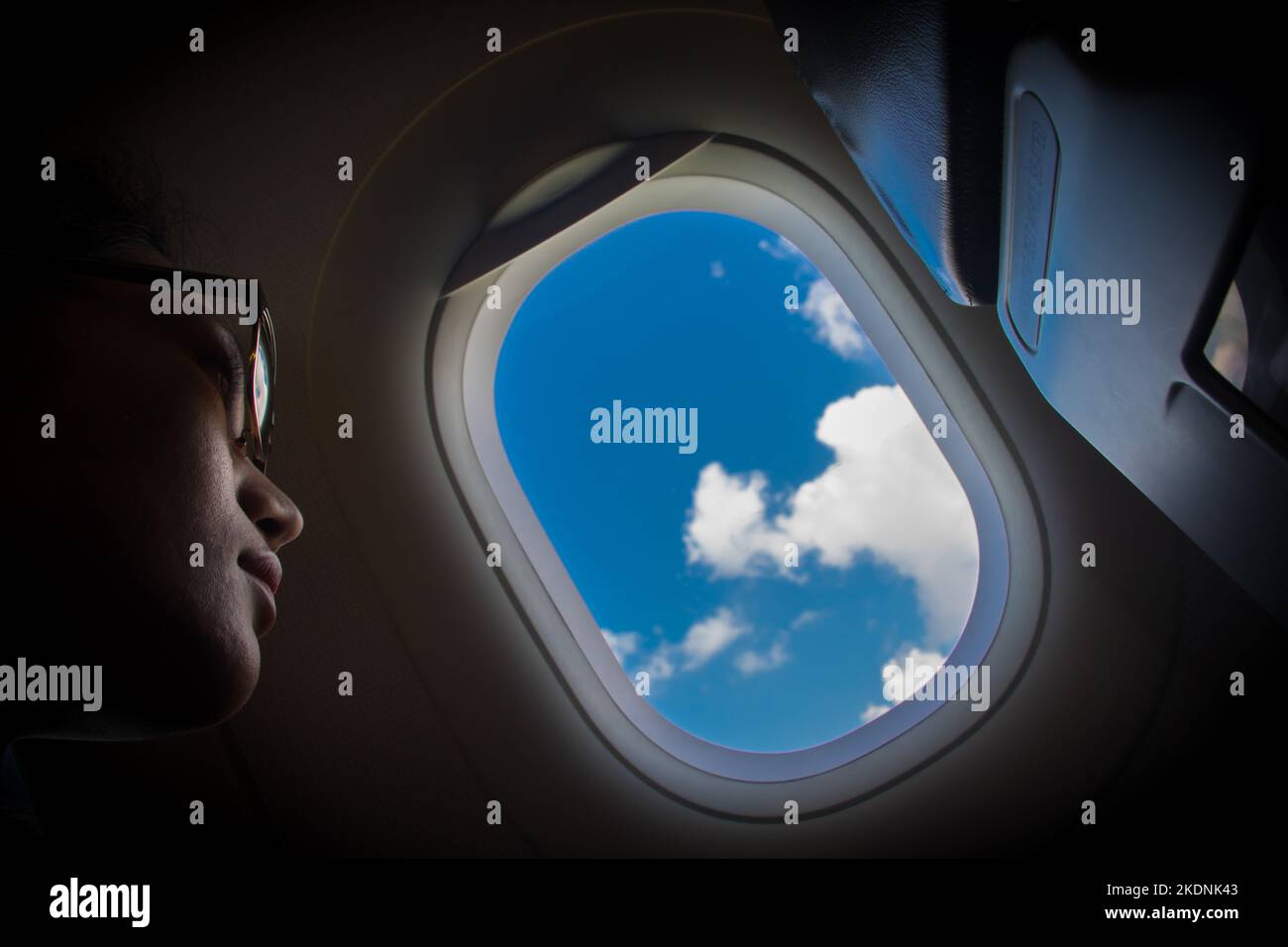 Woman looks out the window of an flying airplane Stock Photo - Alamy