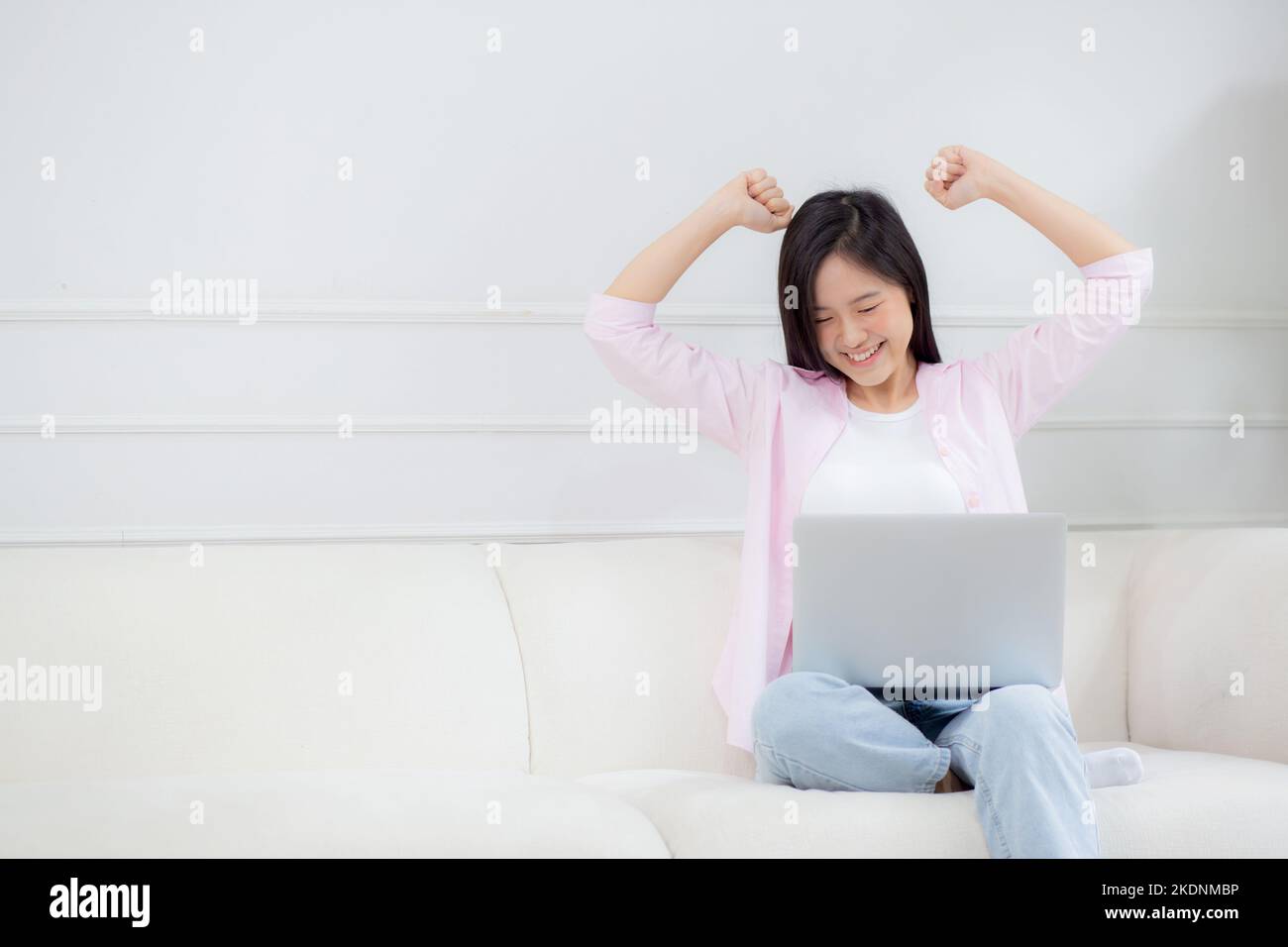 Happiness young asian woman sitting on sofa and working on laptop ...