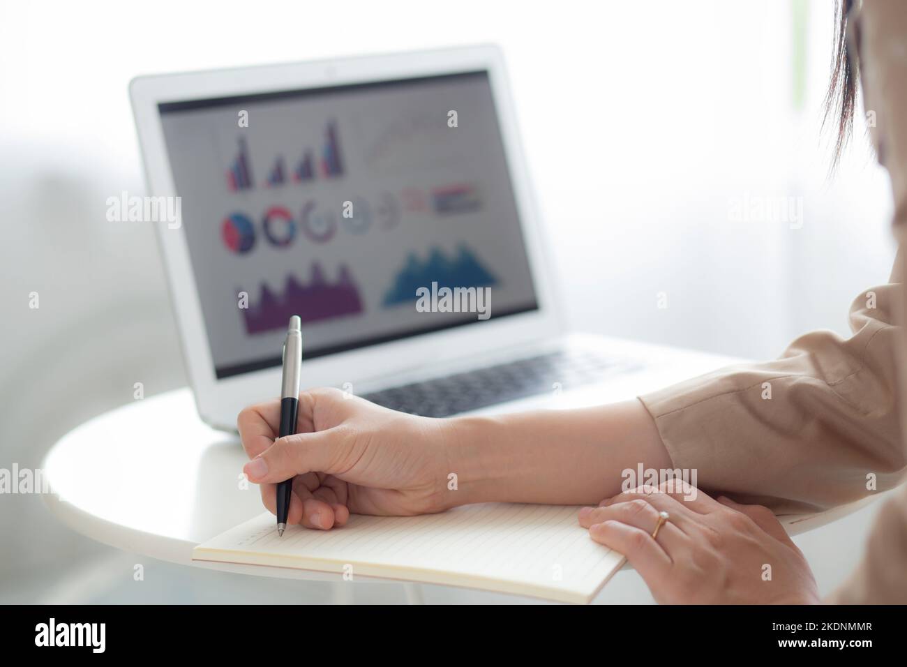 Closeup hands of businesswoman writing and using laptop computer on ...