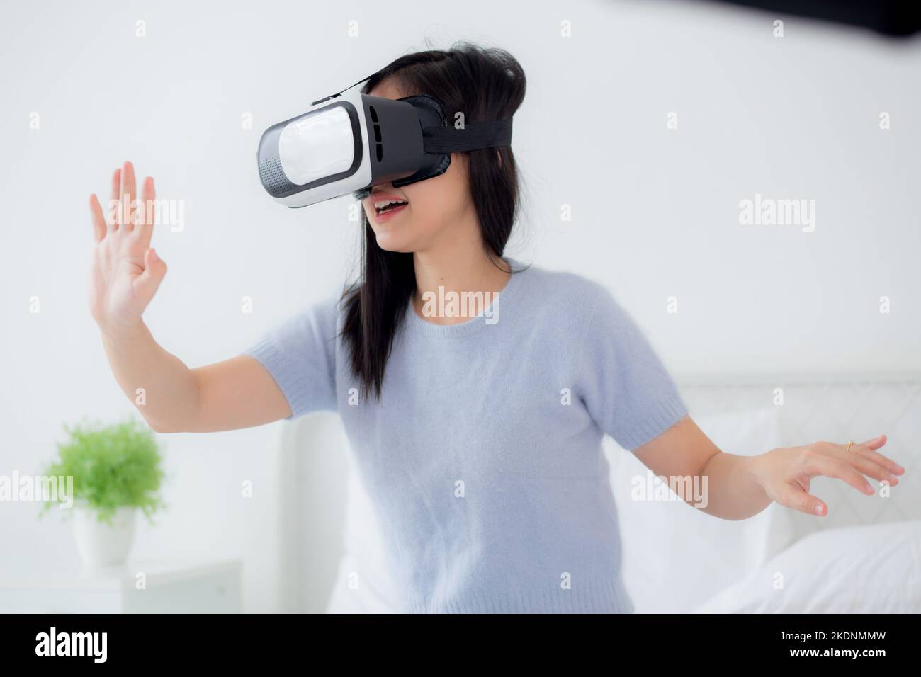 Young asian woman wearing vr headset playing game with excited on bed ...