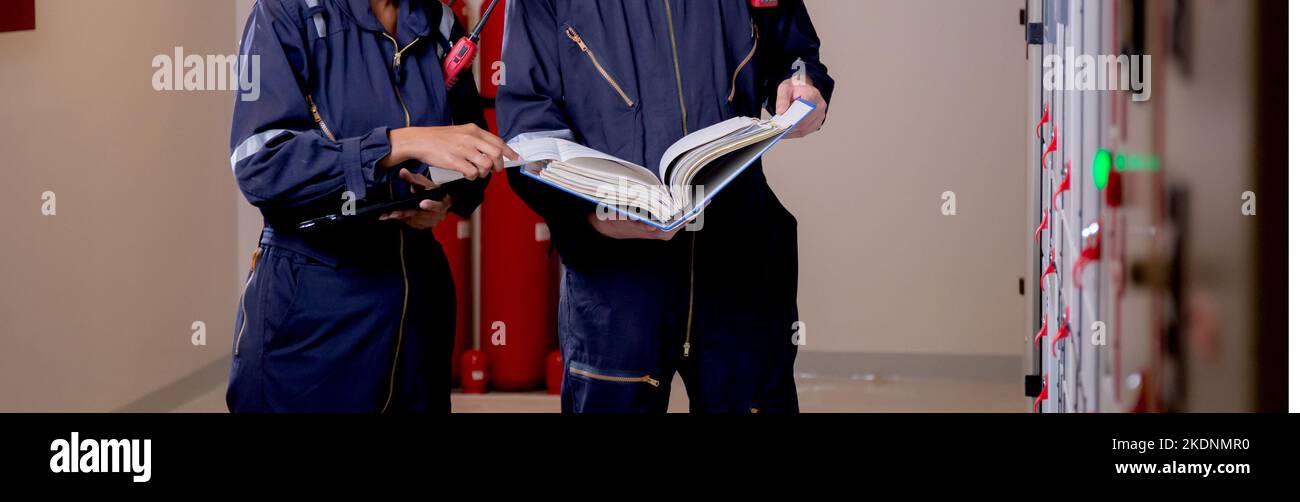 Electrical young woman and man engineer examining maintenance cabinet system electric and ...
