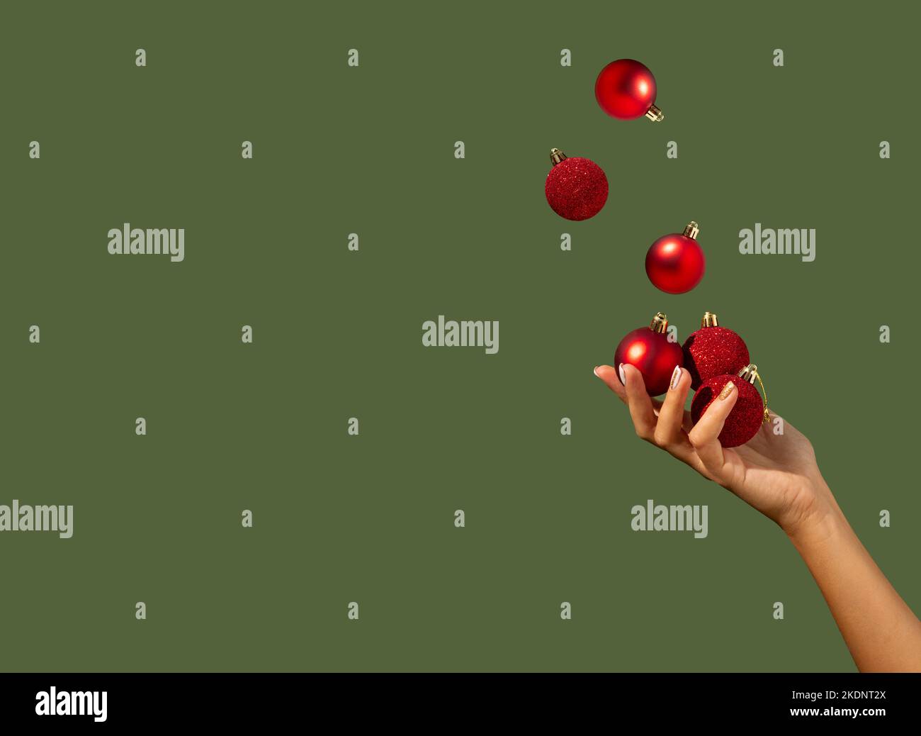 Beautiful woman's hand juggling Christmas baubles on dark green ...