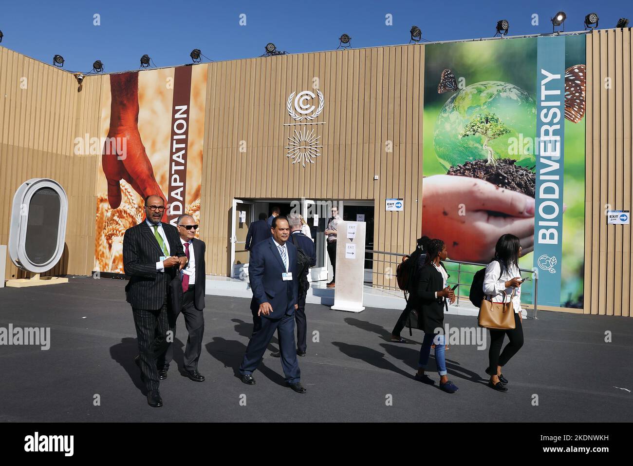 Sharm El Sheikh. 8th Nov, 2022. Participants walk past posters during ...