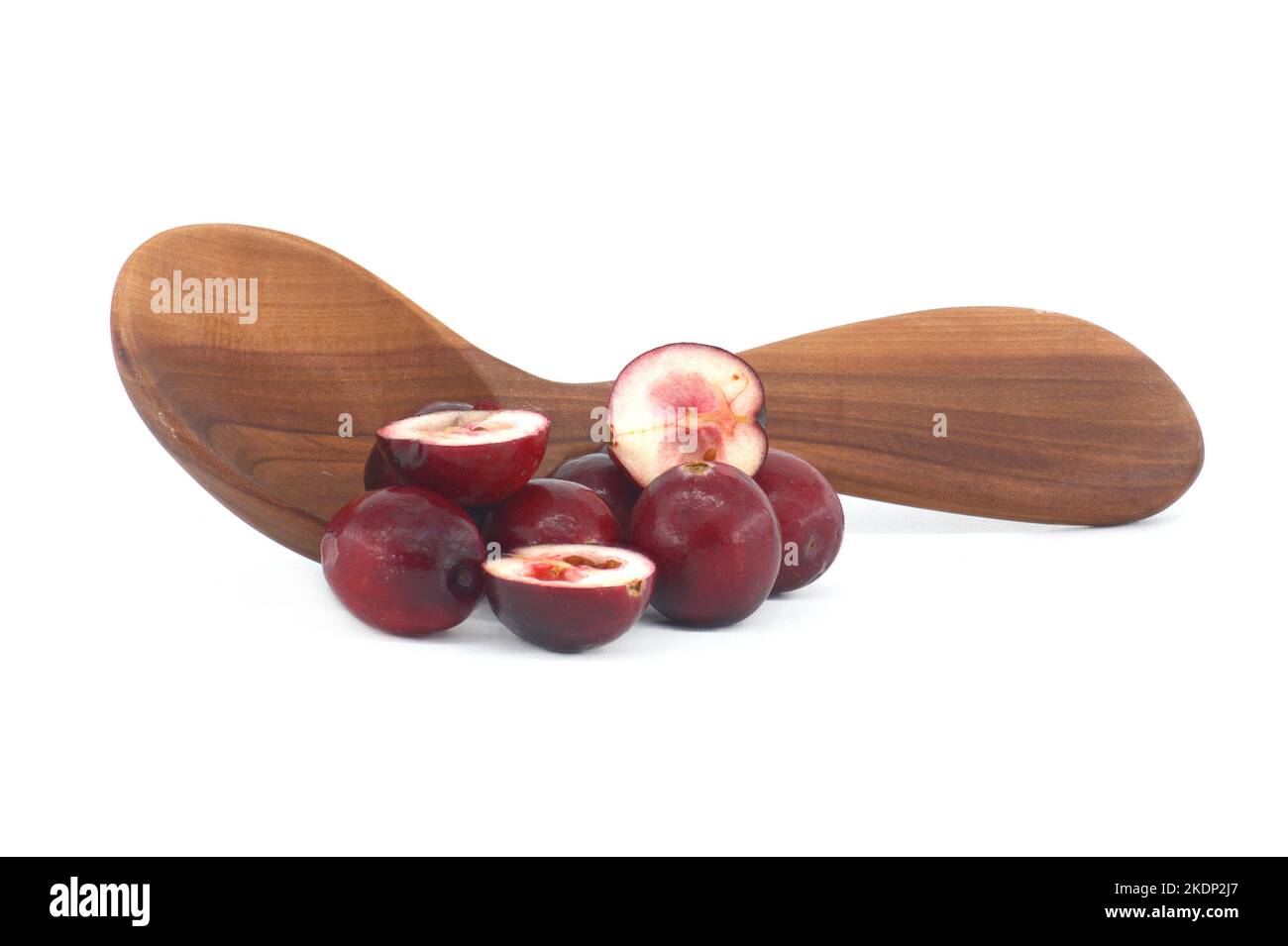 Half cut cranberry berry and fresh cranberries against of wooden spoon ...