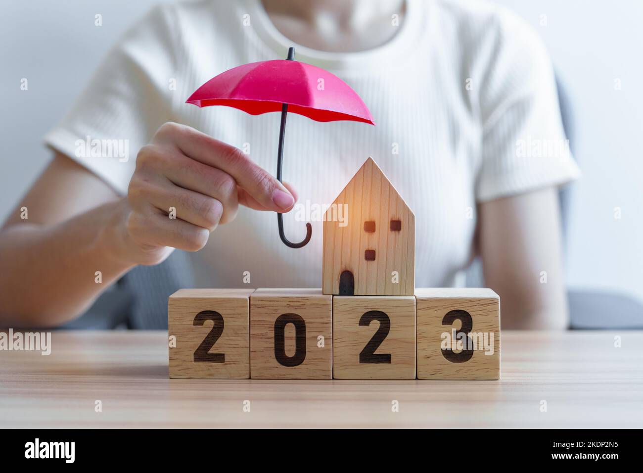 hand holding red Umbrella cover wooden Home model with 2023 Year blocks ...