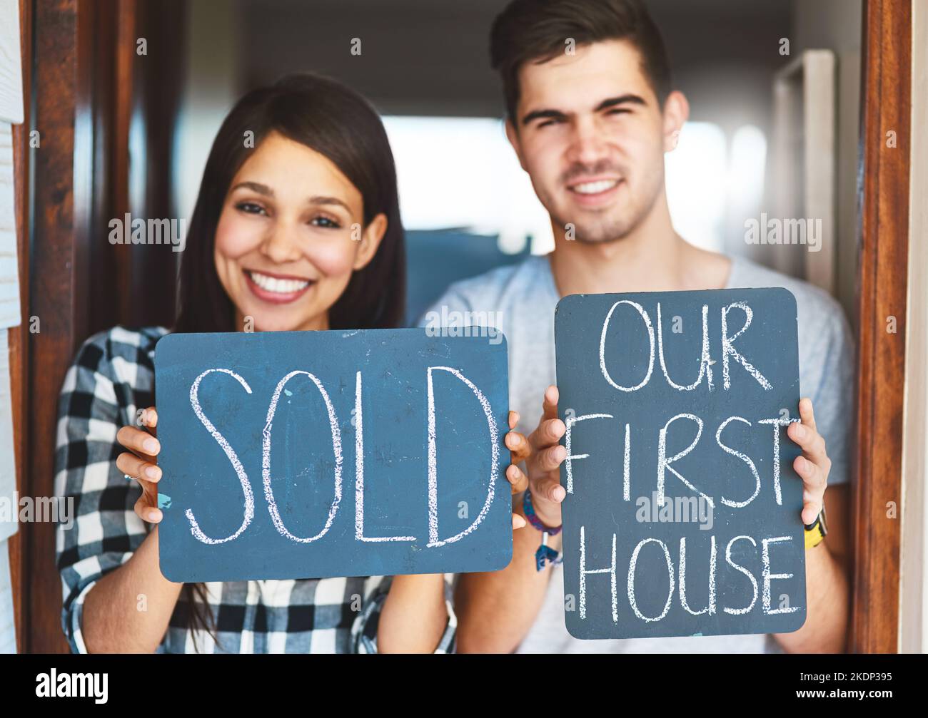 Our story begins here. Portrait of a happy couple holding signs as they ...