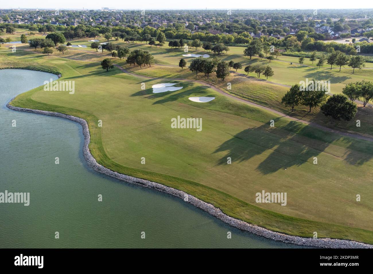 Aerial top view of a green park on the coast of lake. The water in the ...