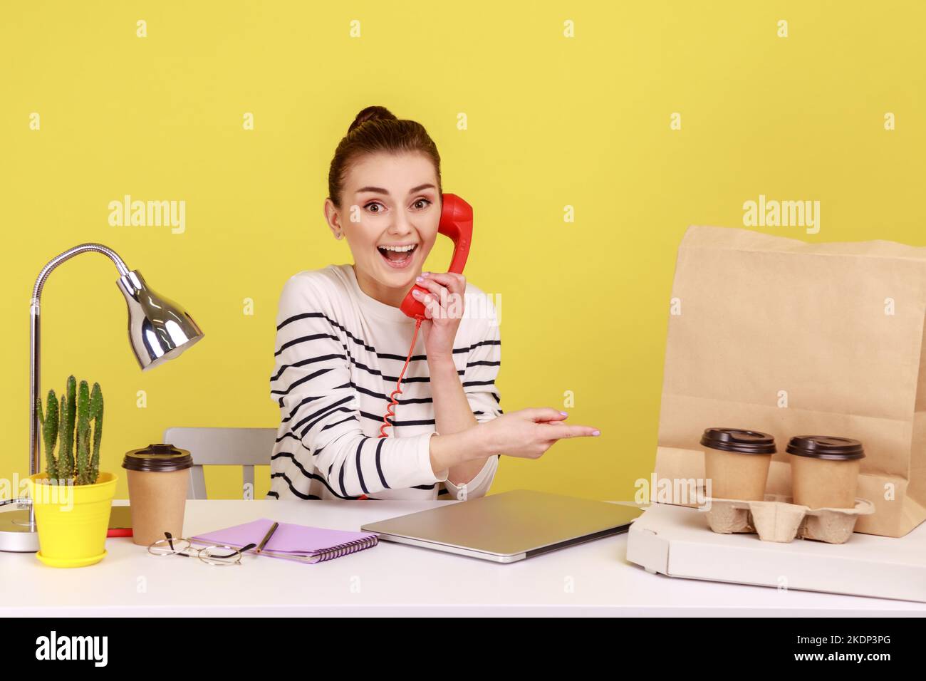 Happy woman pointing at pizza box cups of coffee and paper bag with ...