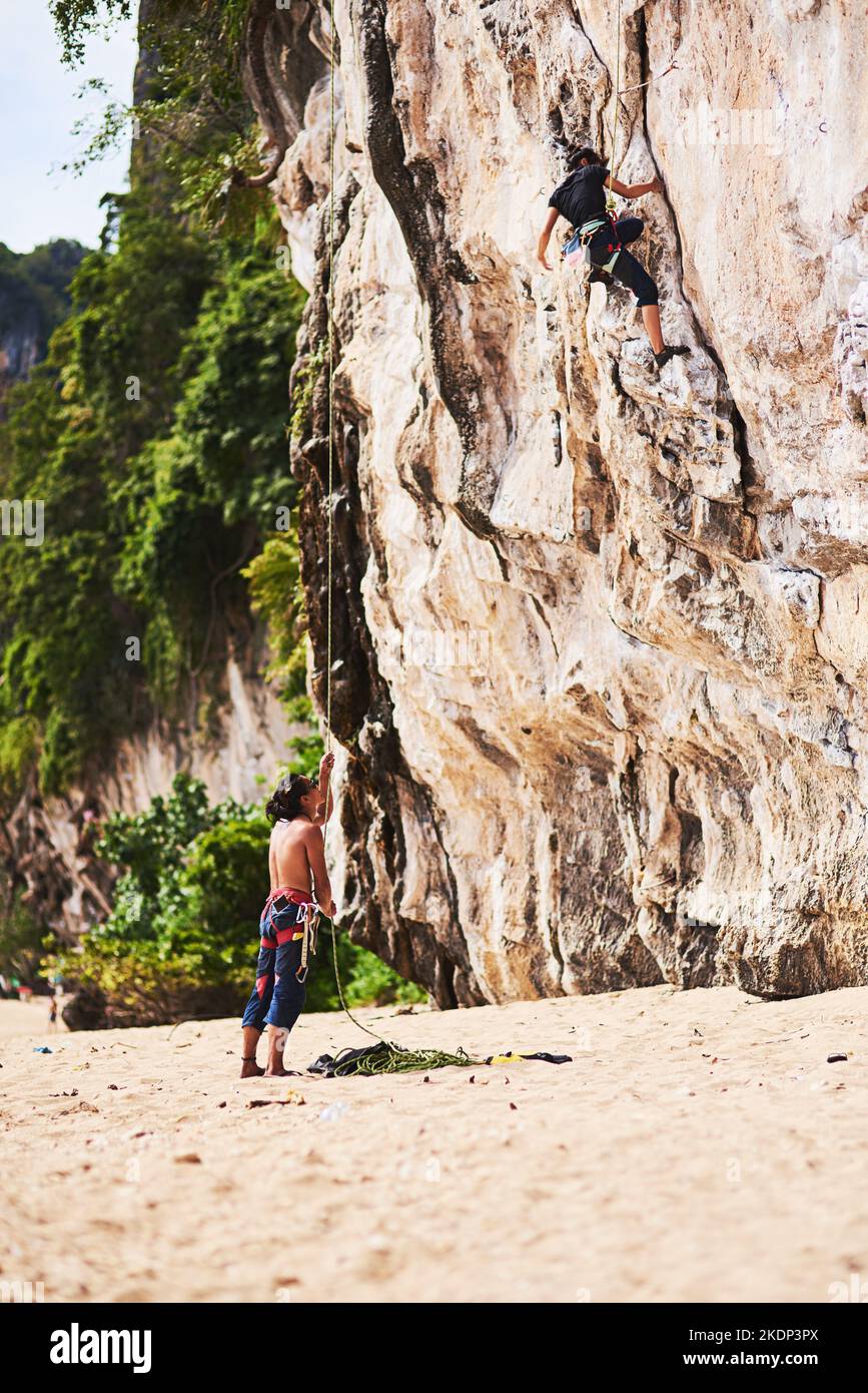 Getting to the top. a young rock climber scaling a cliff face Stock ...