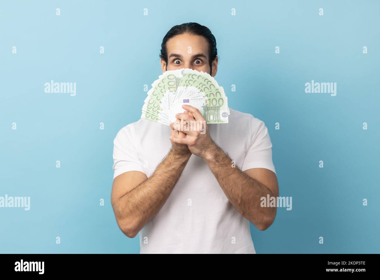 Man with beard wearing white T-shirt covering face with money and ...