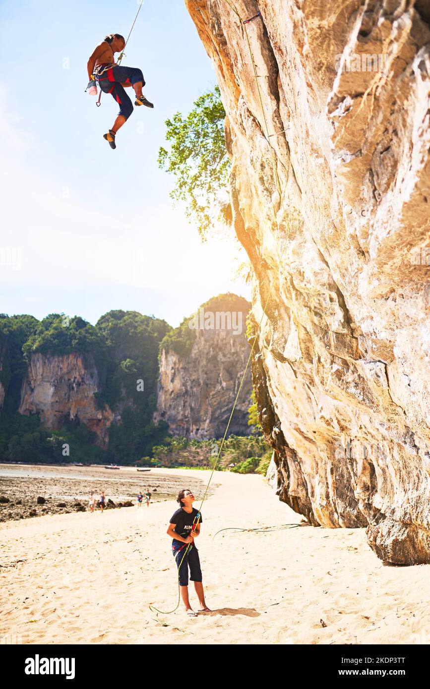 Time to reach new heights. two young people rock climbing on a sunny ...