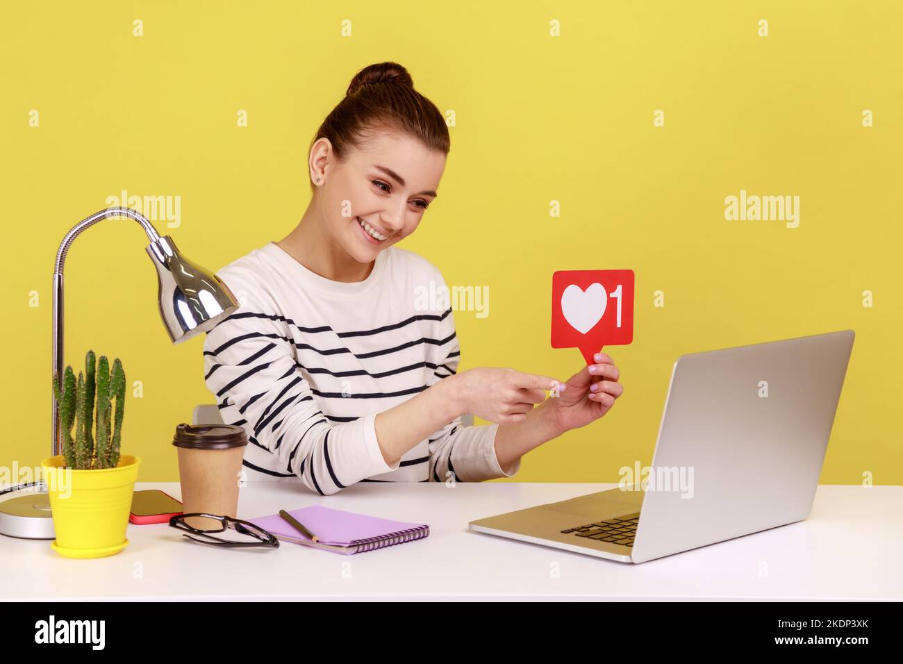 Smiling optimistic woman sitting at workplace, asking to rate her posts ...