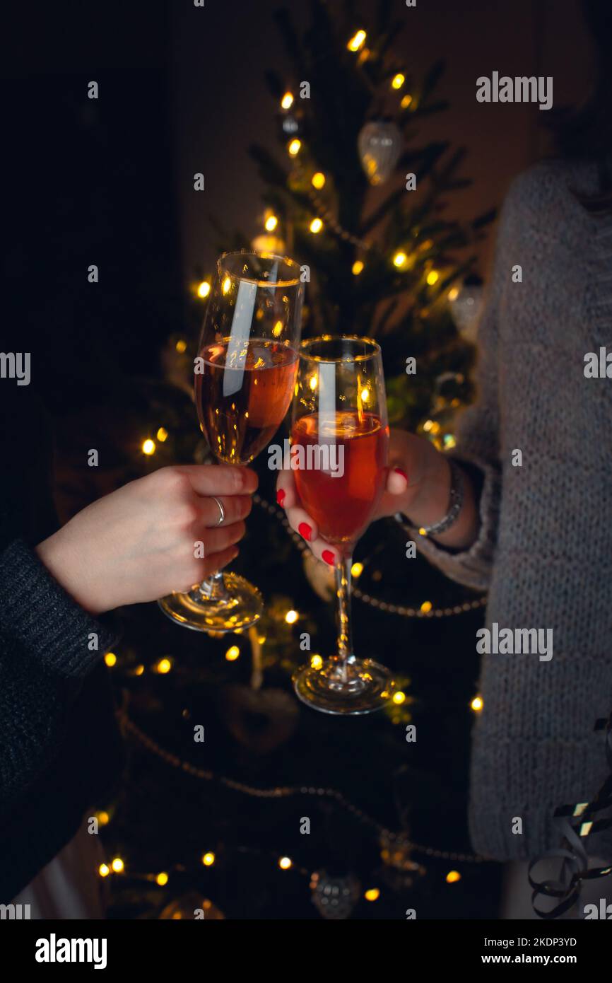 Two girls with glasses of champagne near the Christmas tree for ...