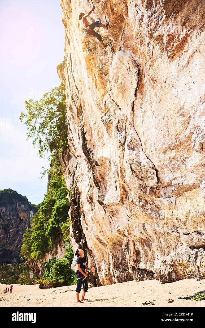 Getting a grip on adventure sports. two young people rock climbing on a ...