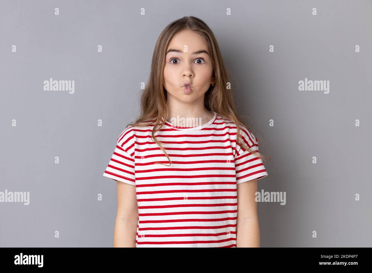 Funny surprised little girl wearing striped T-shirt making fish face ...