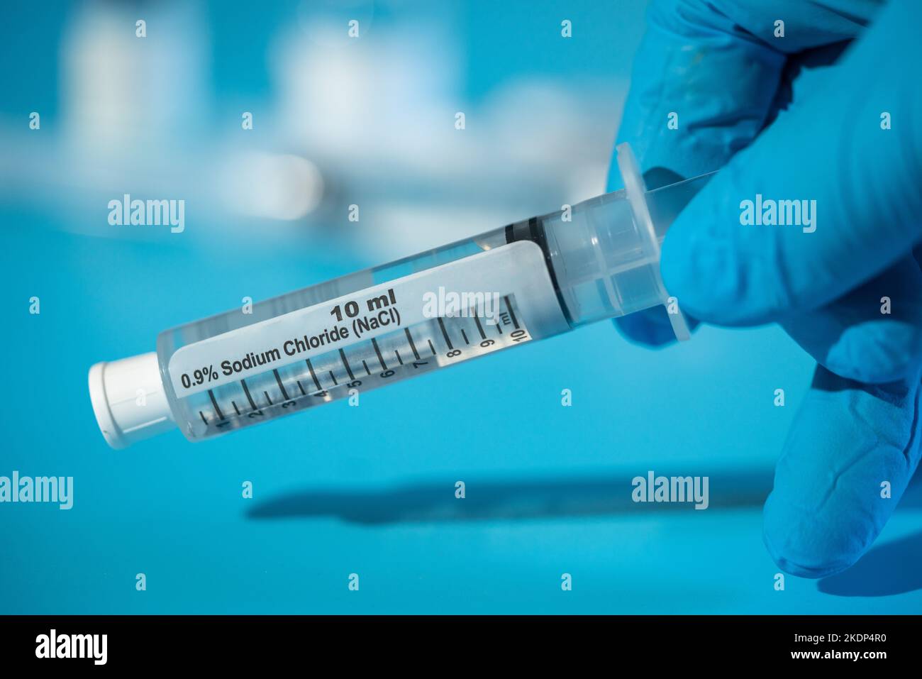 medical syringe with sodium chloride in a doctor's hand on a blue ...