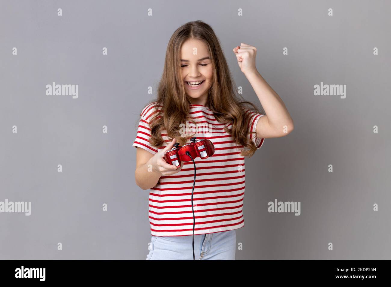 Portrait of little girl wearing striped T-shirt holding hand red ...
