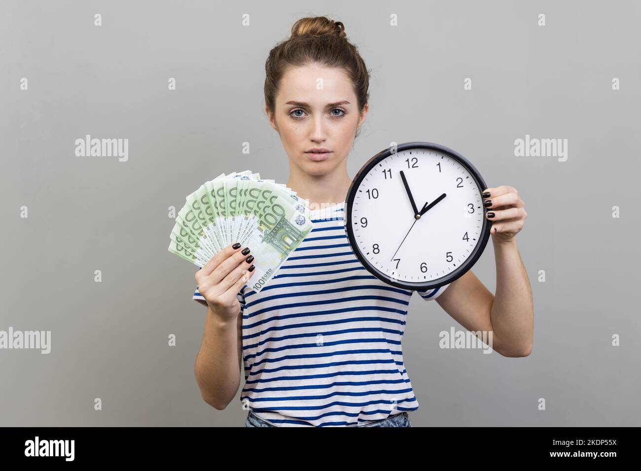 Portrait of strict serious woman with bun hairstyle wearing striped T ...