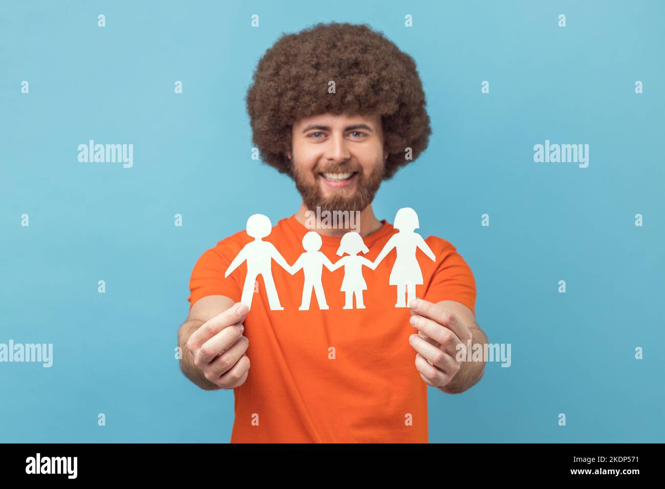 Portrait of smiling satisfied man with Afro hairstyle wearing orange T ...
