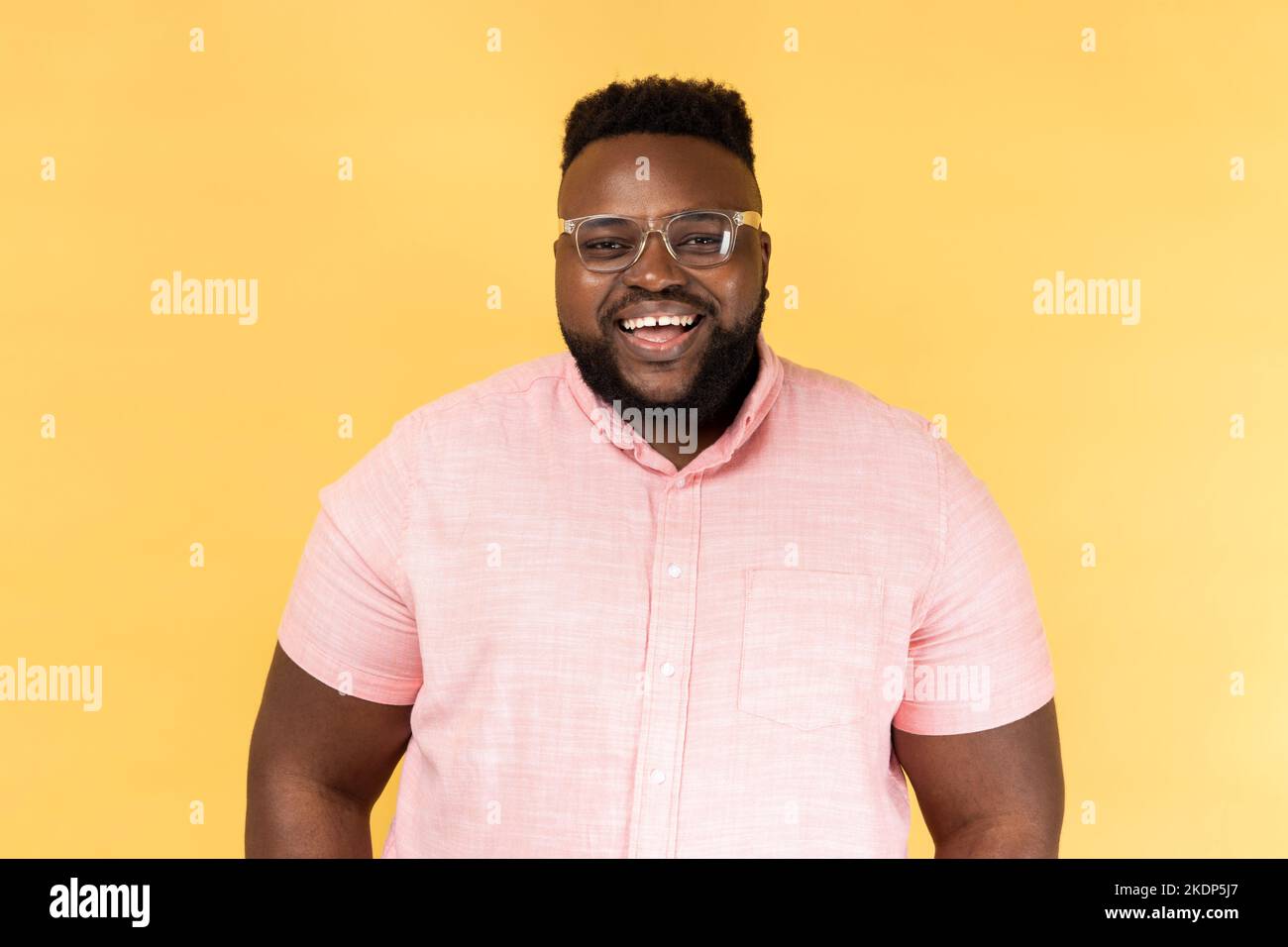 Portrait of smiling positive man wearing pink shirt and optical glasses ...