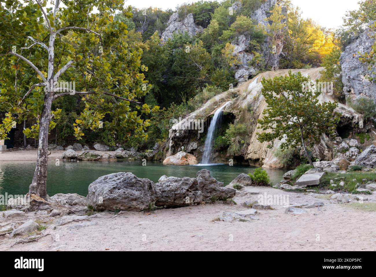 Water cascading over rocks into a natural pool at Turner Falls in ...