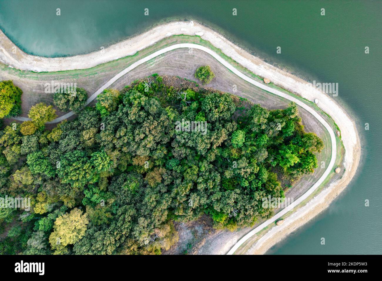 Aerial view of island with green trees and roads surrounded by sea or ...