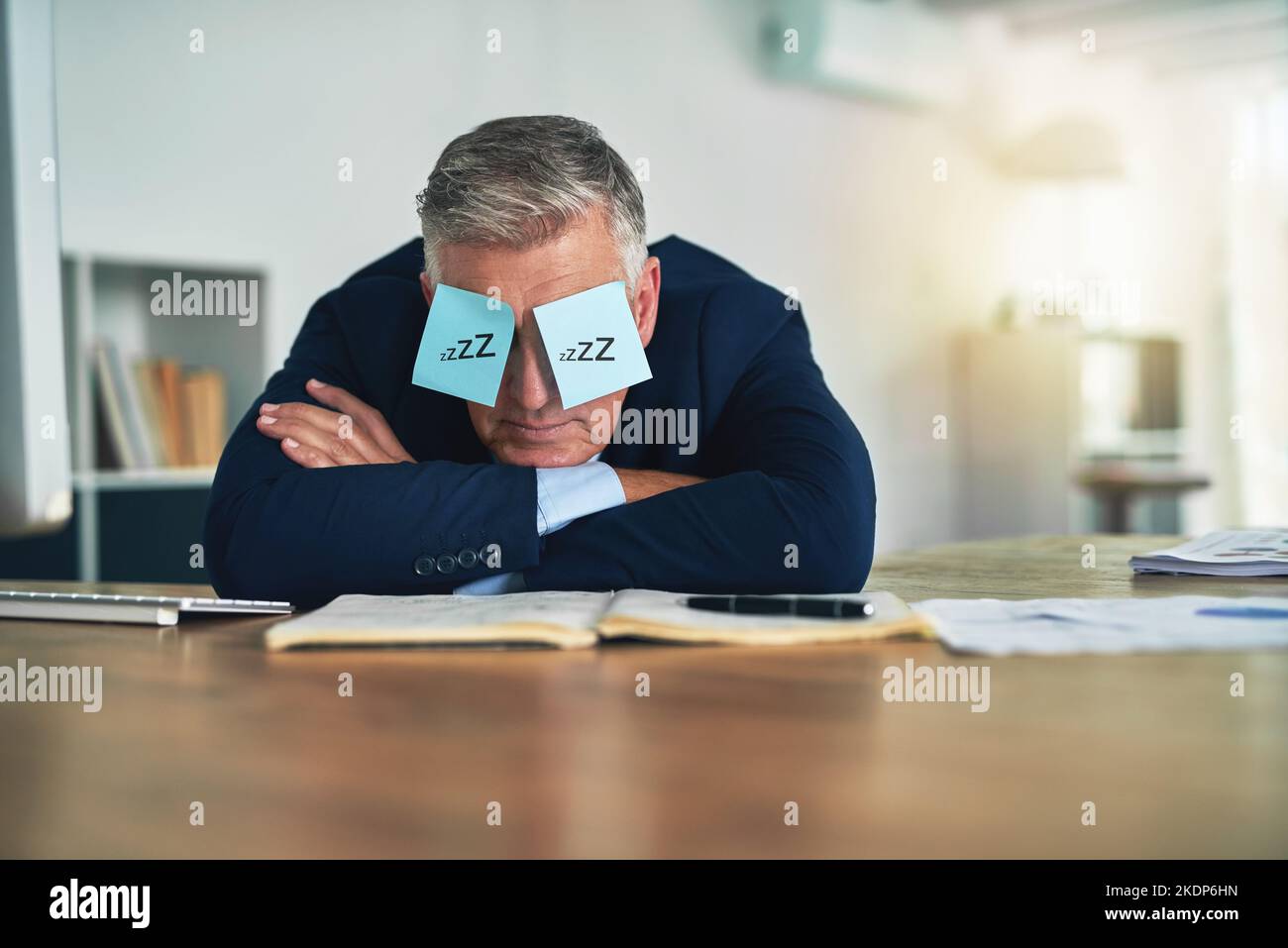 Time for a quick recharge. a tired businessman napping at his desk with ...