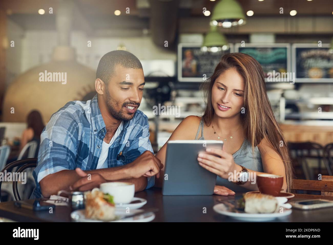 Cafe connections. a young couple using a digital tablet while sitting ...