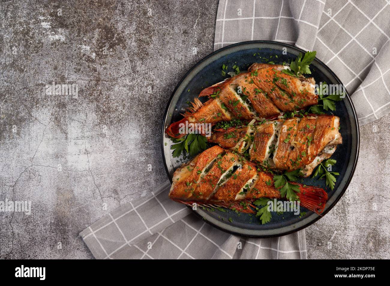 Pan Fried Rose fish with herbs on a round plate on a dark background ...