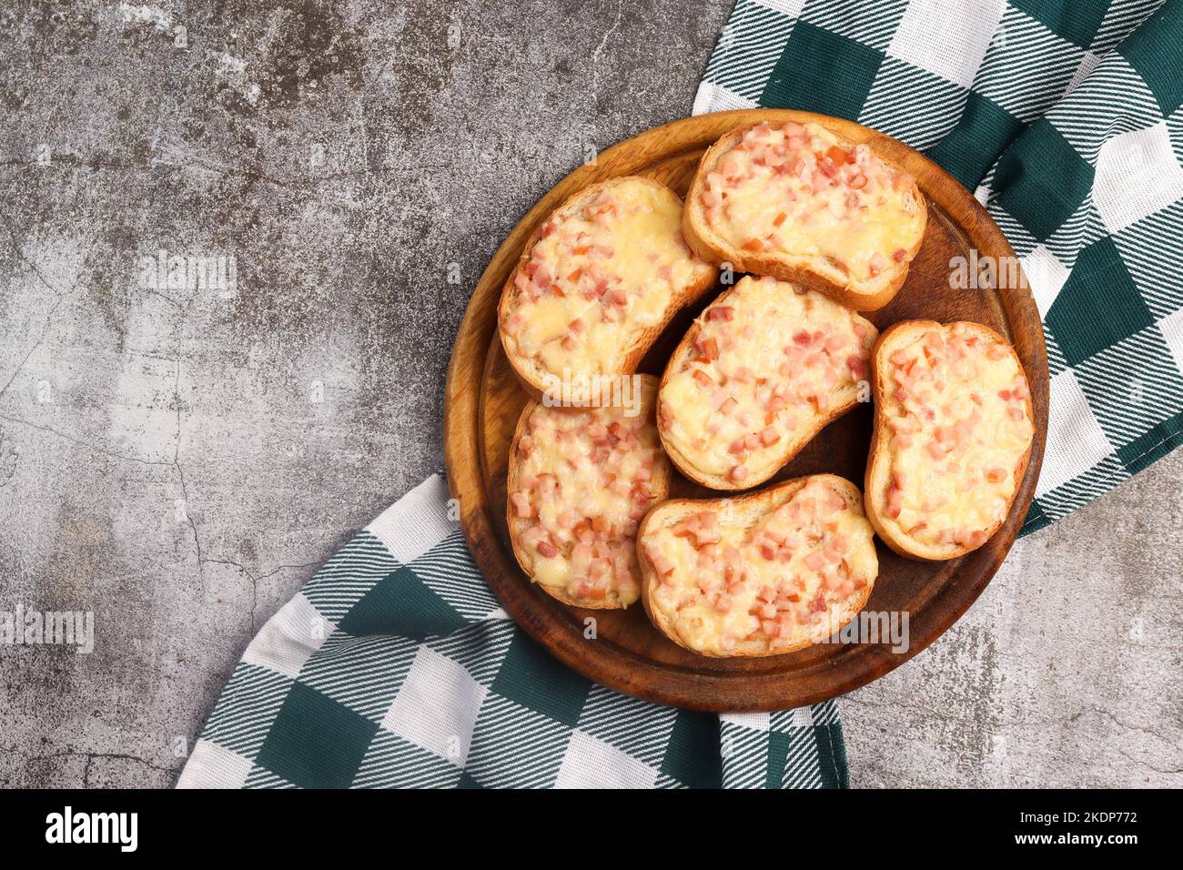 Warm open faced Ham and cheese sandwiches on a round wooden cutting ...