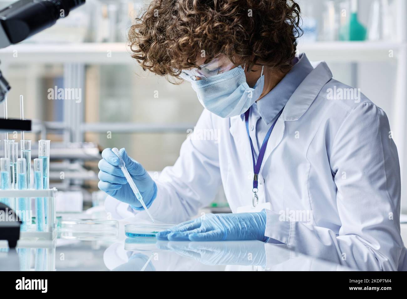 Young female researcher mixing two chemical substances in petri dish ...