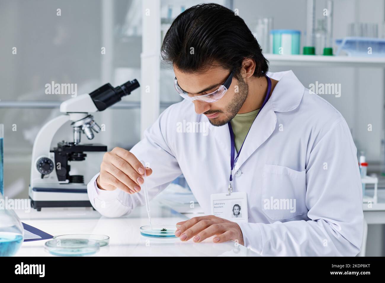 Young clinician in protective eyeglasses bending over workplace and ...