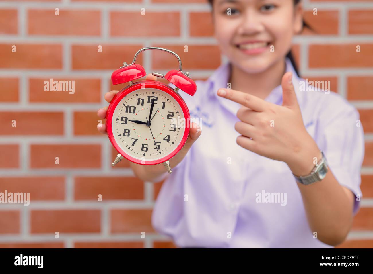 happy Asian school teen girl smiling hand pointing at alarm clock for ...