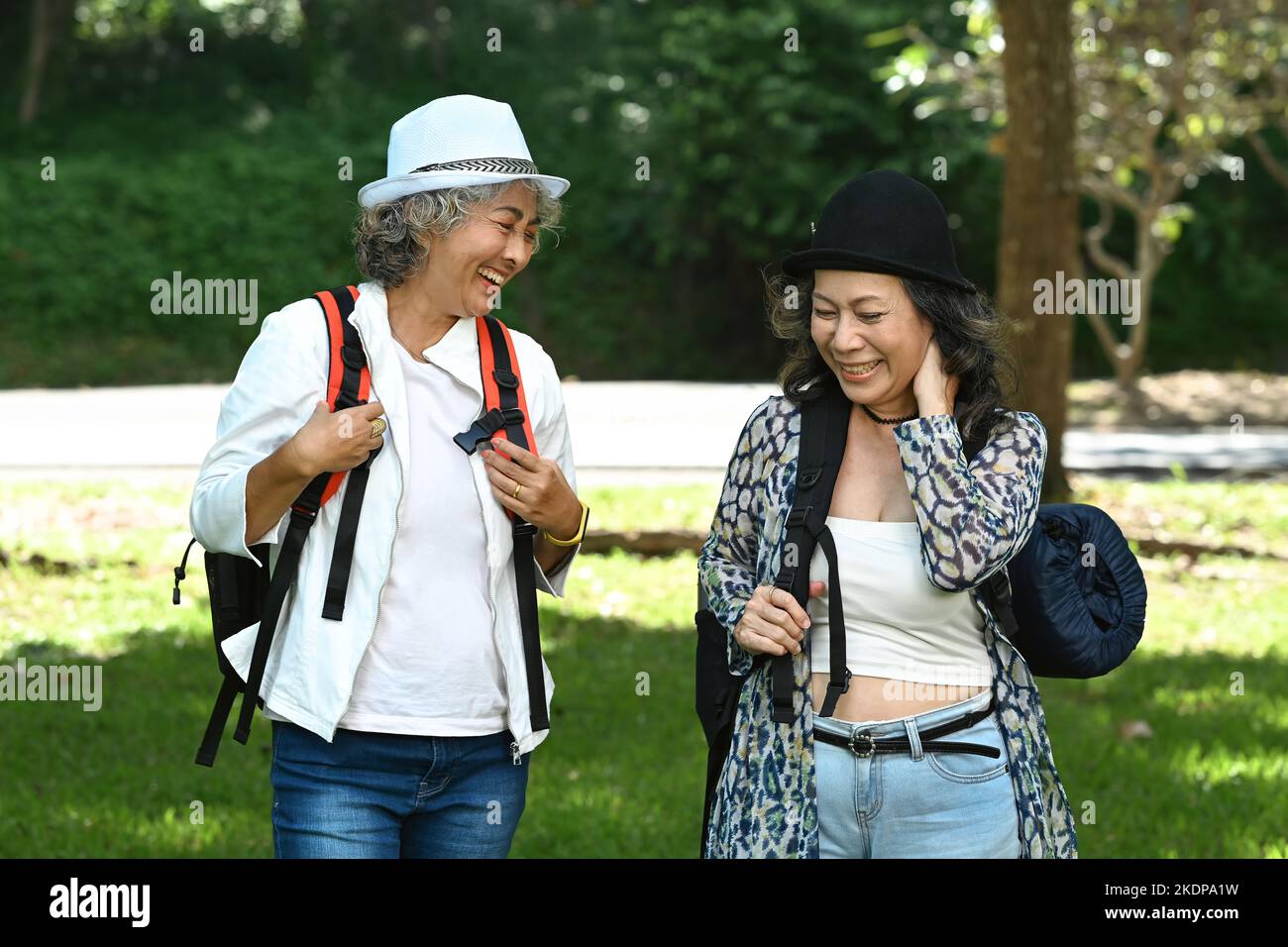 Happy middle aged female friends talking each other while walking at ...