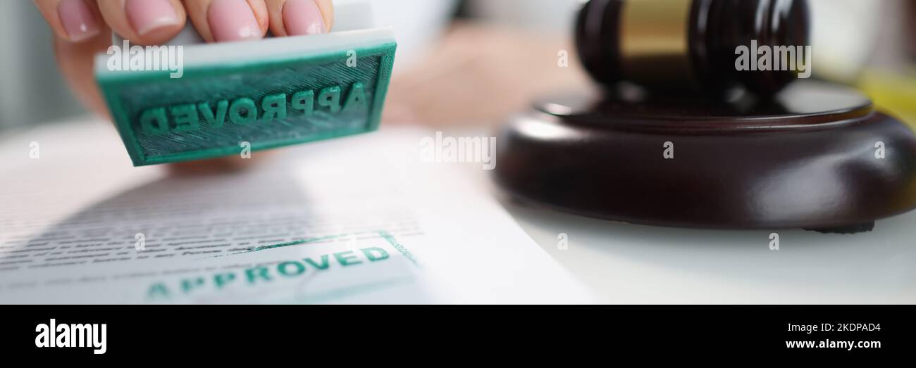 Female hand holding approved stamp, judge gavel Stock Photo - Alamy