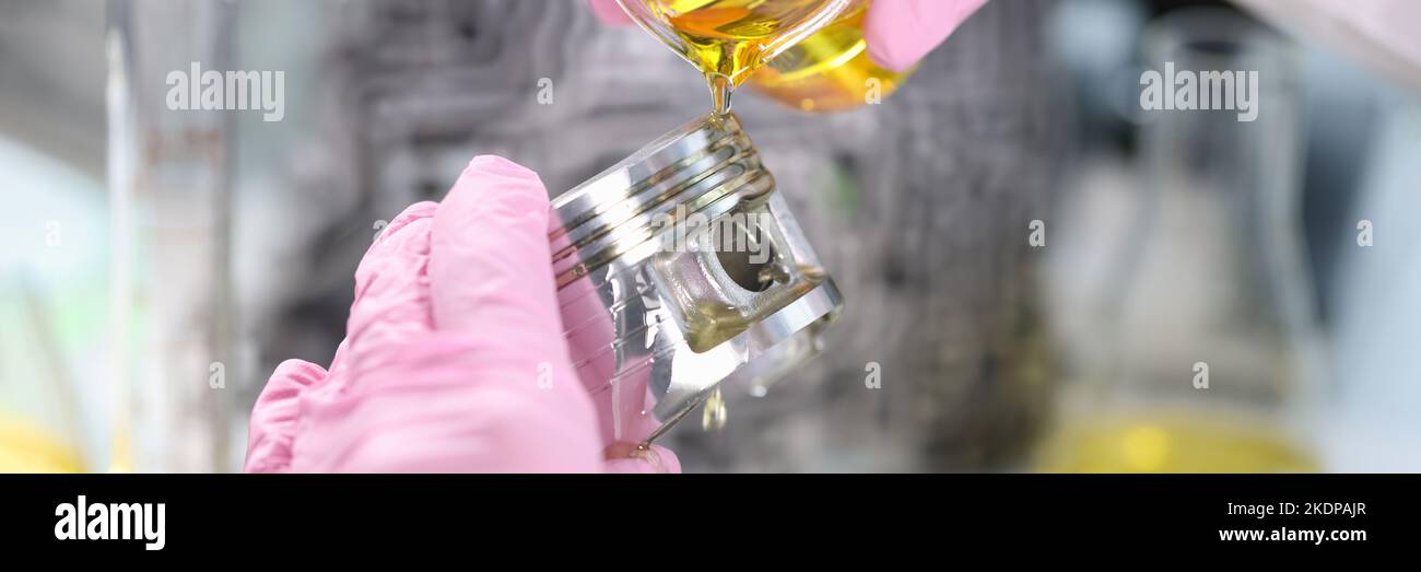 Person hand in gloves holding piston and pours lubricating oil on it ...