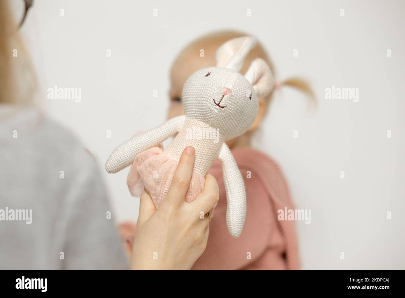 Cute stuffed animal in female hand on blurred white background ...