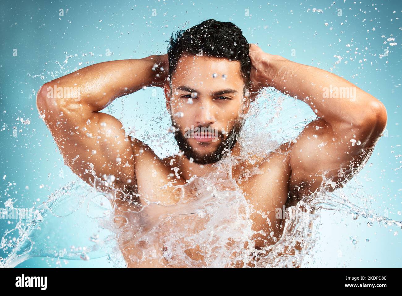 Water, splash and man washing his body on a blue studio background for health and wellness ...