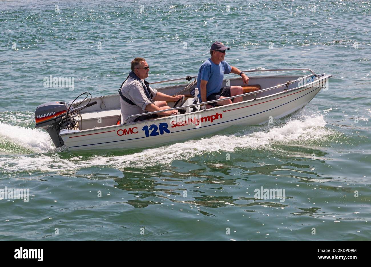 Two men in OMC 12R Sea Nymph boat motoring to the entrance to Christchurch Harbour, known as The ...